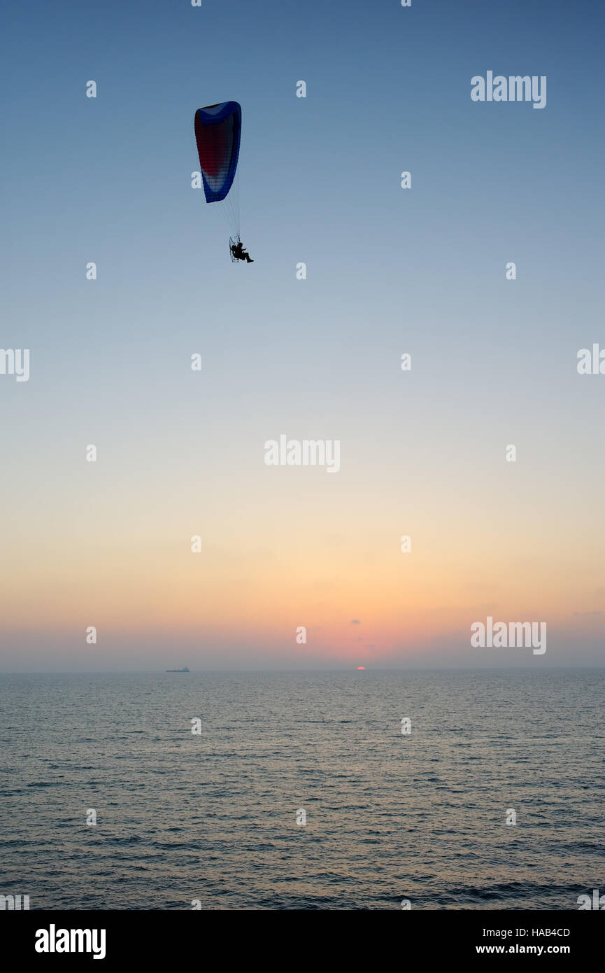 Powered paraglider flying over the sea at sunset sky background Stock ...