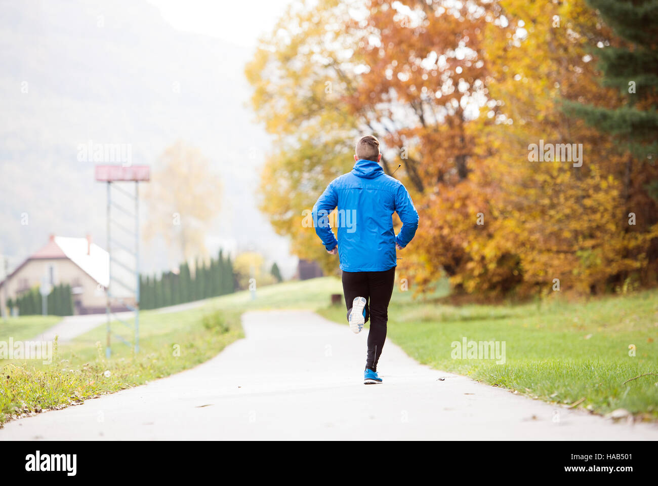 Handsome young athlete running on concrete path, rear view Stock Photo ...
