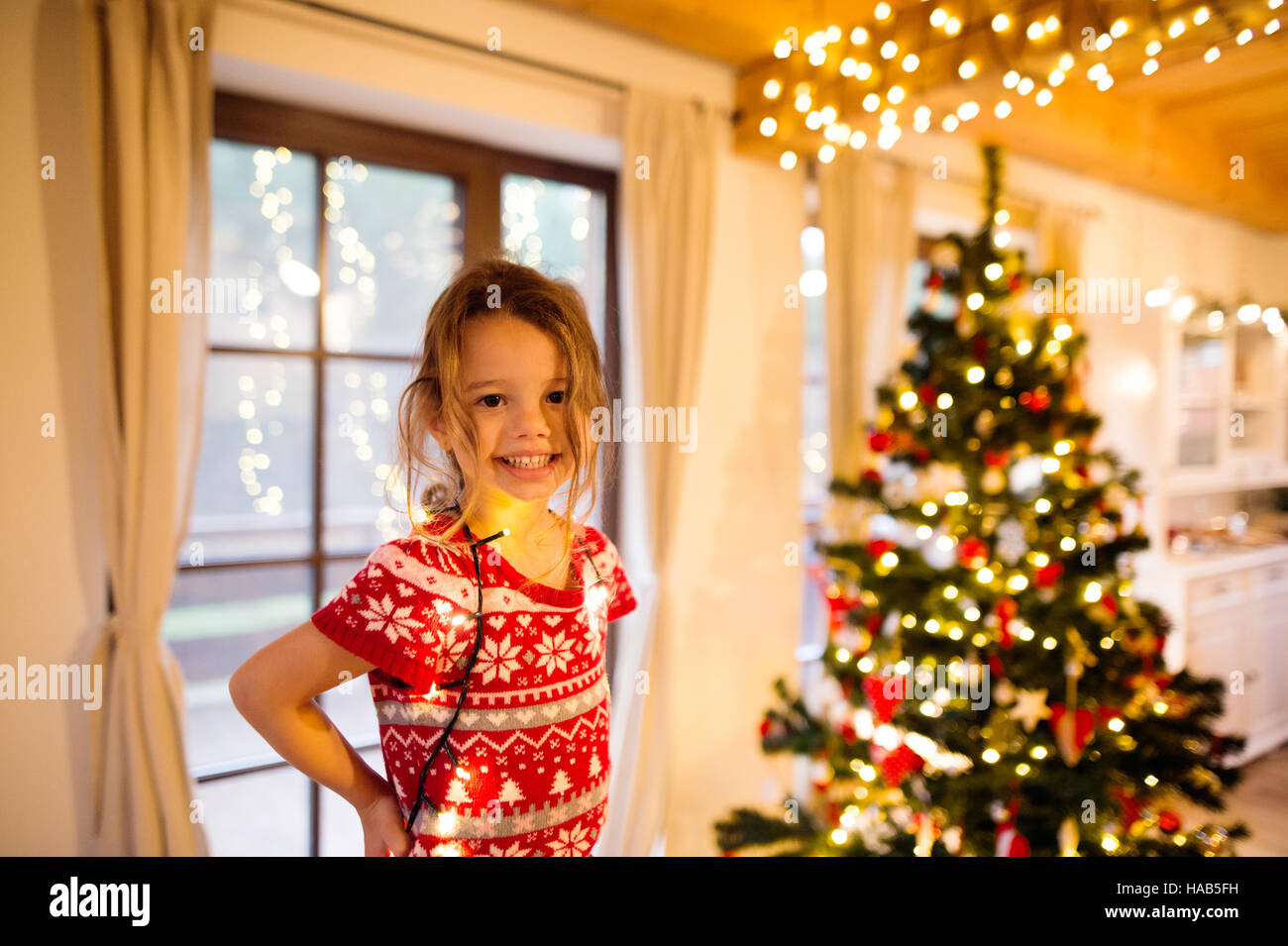 Little girl decorating Christmas tree tangled in chain lights Stock ...