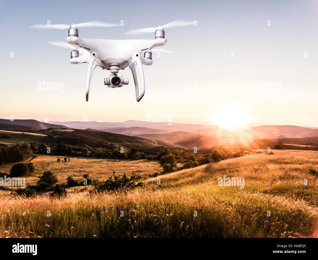 Hovering drone taking pictures of green nature at sunset Stock Photo ...