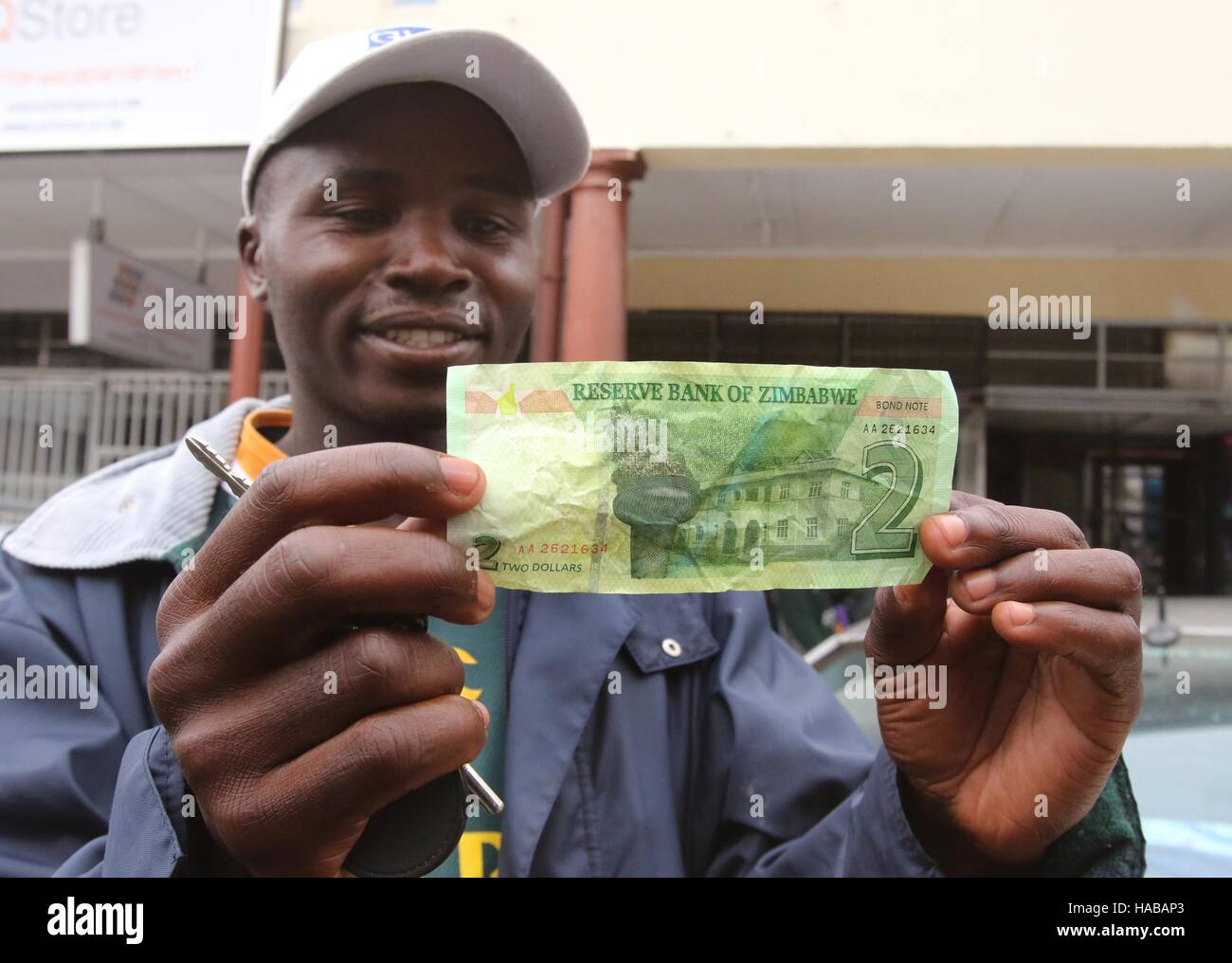 Harare. 29th Nov, 2016. A man displays a new bond note in front of a ...
