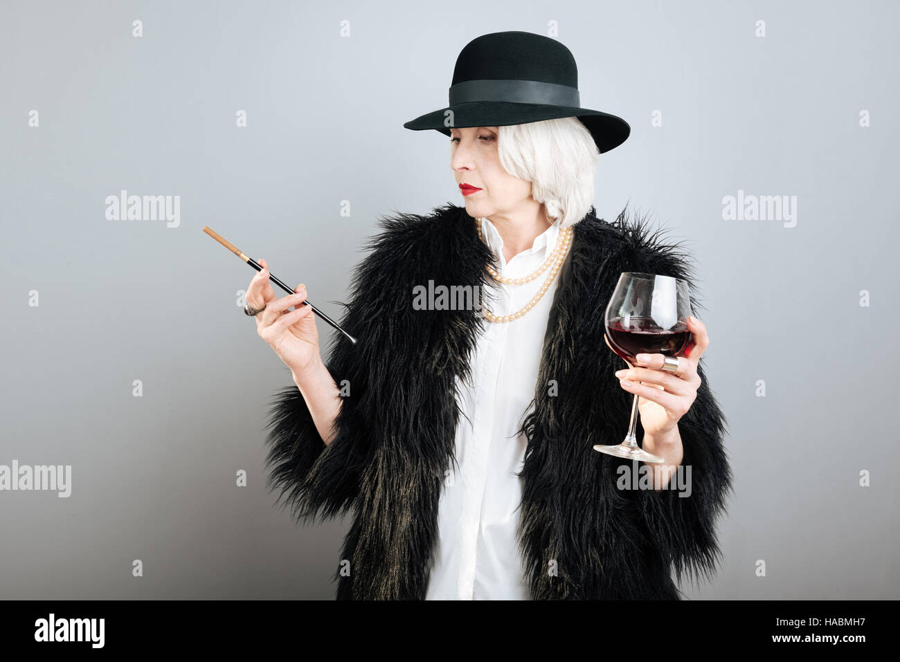 Stylish serious lady holding cigarette and wineglass Stock Photo - Alamy