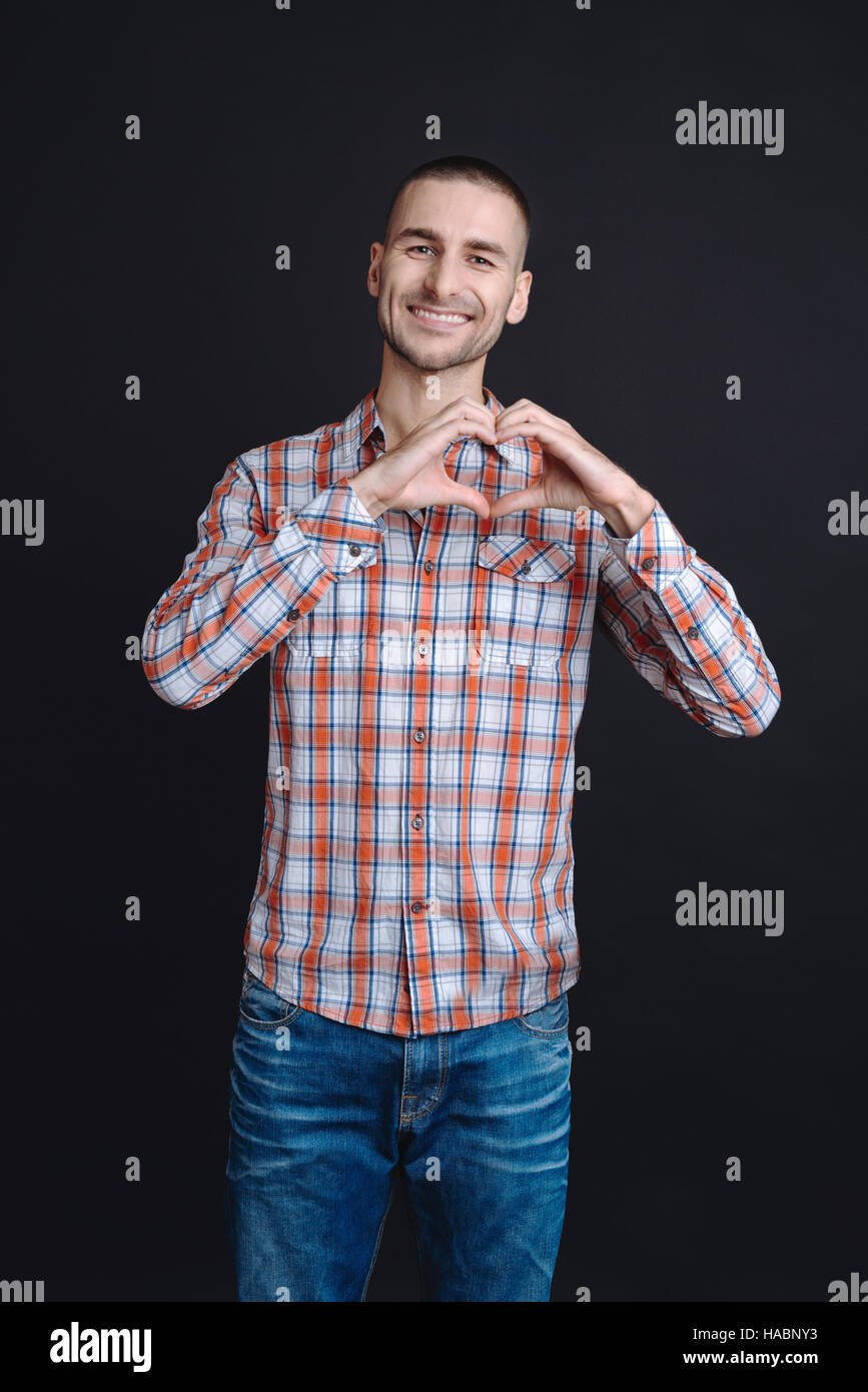 Positive delighted man showing heart Stock Photo - Alamy