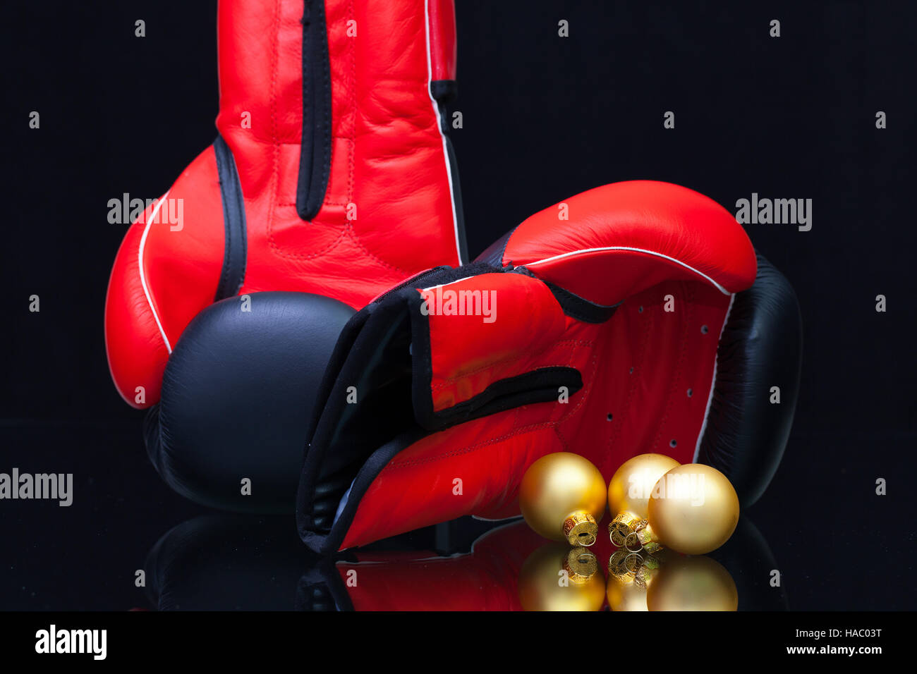 Red and black boxing gloves and Christmas decoration on black glass ...
