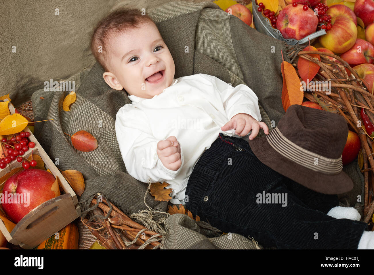autumn little boy lie on yellow fall leaves, apples, pumpkin and ...