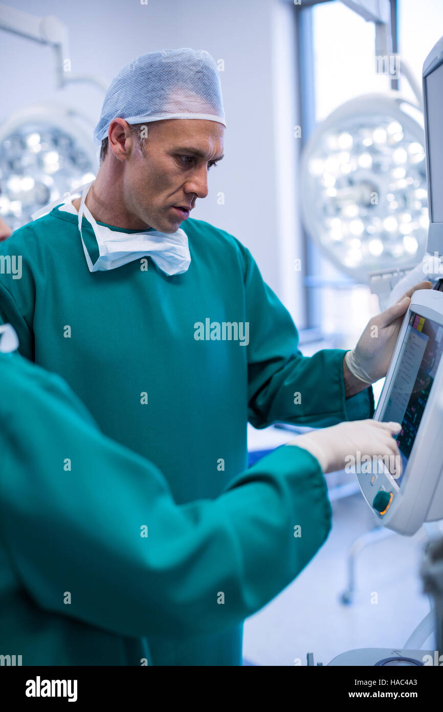 Surgeons discussing a report on surgical monitor in operation room ...