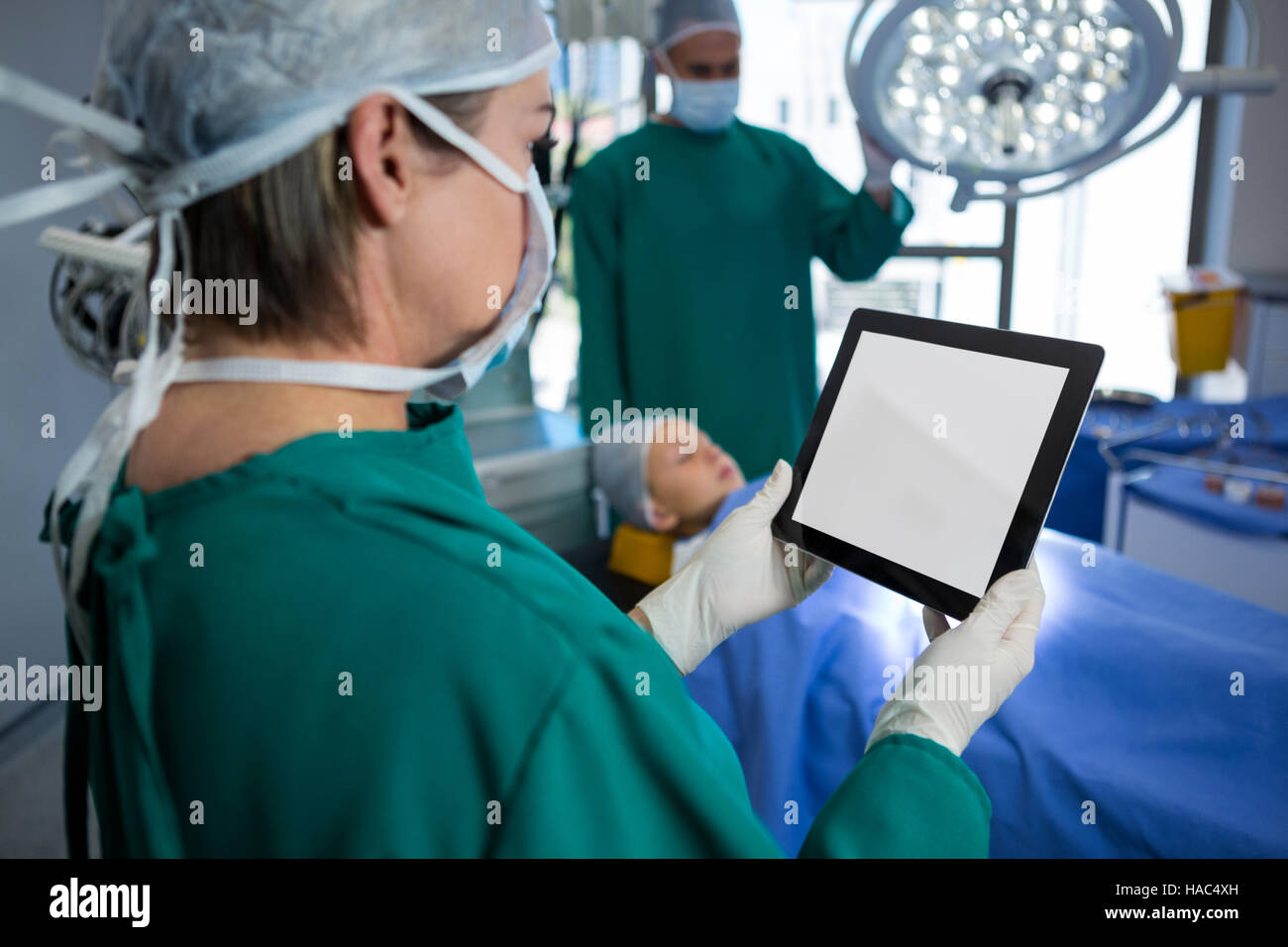 Surgeon using digital tablet while operating patient Stock Photo - Alamy