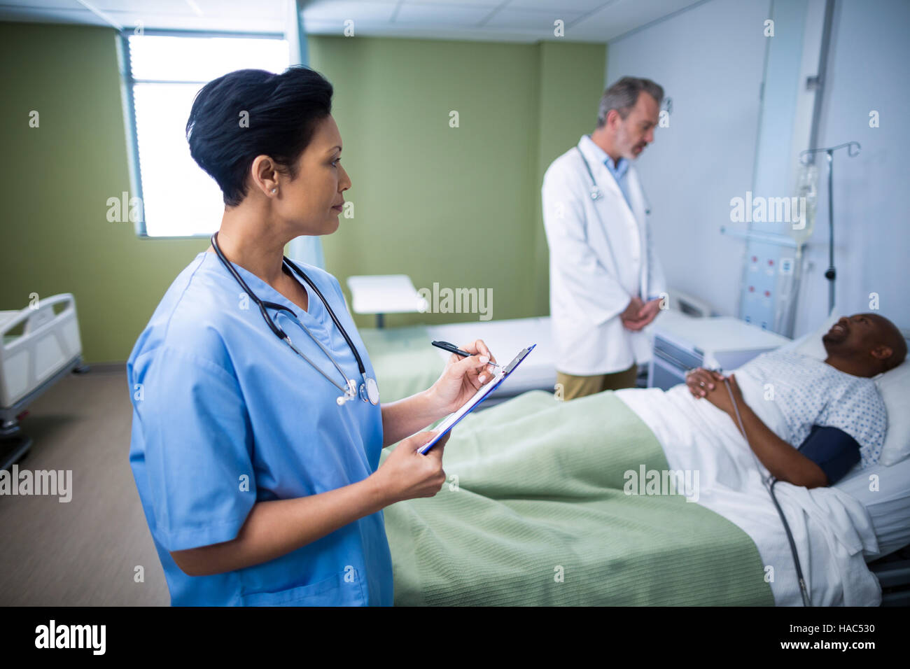 Female nurse writing on clipboard during visit in ward Stock Photo - Alamy