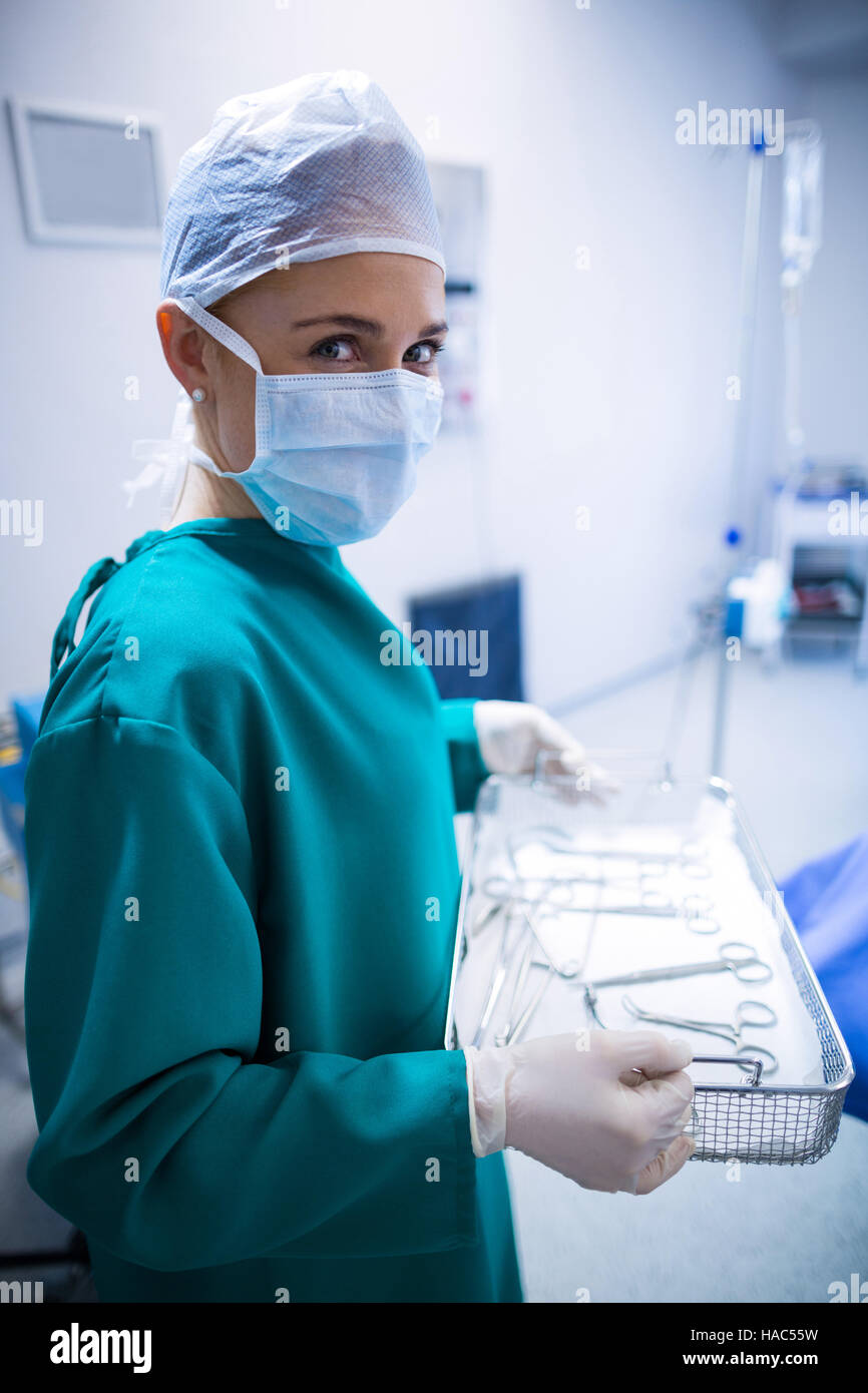 Portrait of female surgeon holding surgical tray in operation theater ...