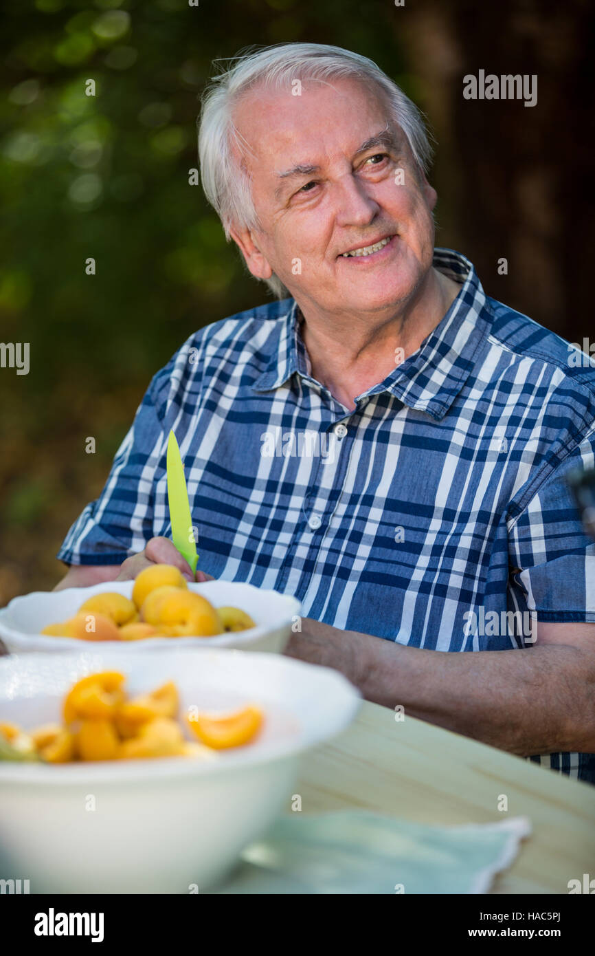 Senior man sitting at table with apricot fruits in bowl Stock Photo - Alamy