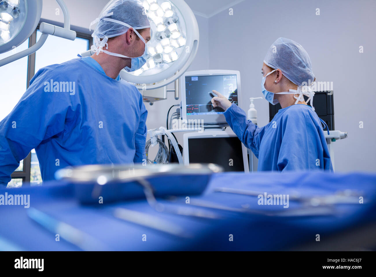 Male and female nurse using patien monitoring machine in operation ...