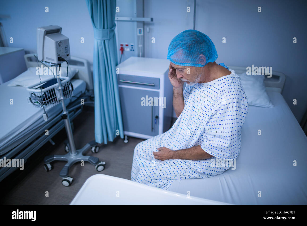 Sad patient sitting on bed with hand on head Stock Photo - Alamy