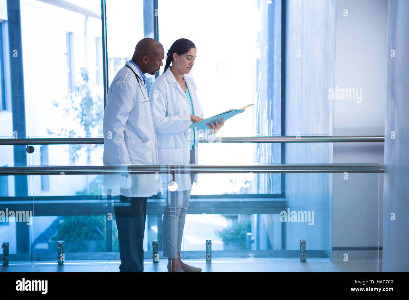 Male and female doctors having over file in corridor Stock Photo - Alamy