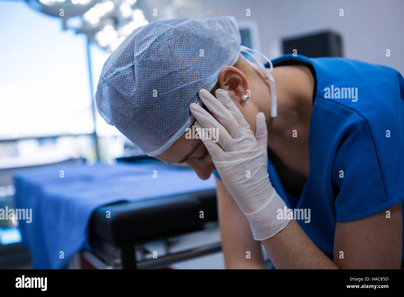 Sad female nurse sitting in operation theater Stock Photo - Alamy