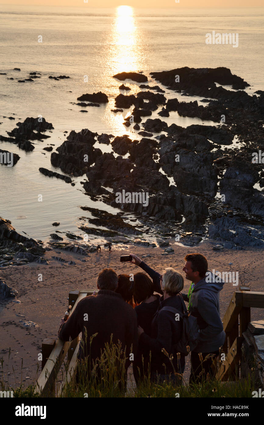 Tourists taking a selfie at sunset, Rockham Bay, near Mortehoe, Devon ...