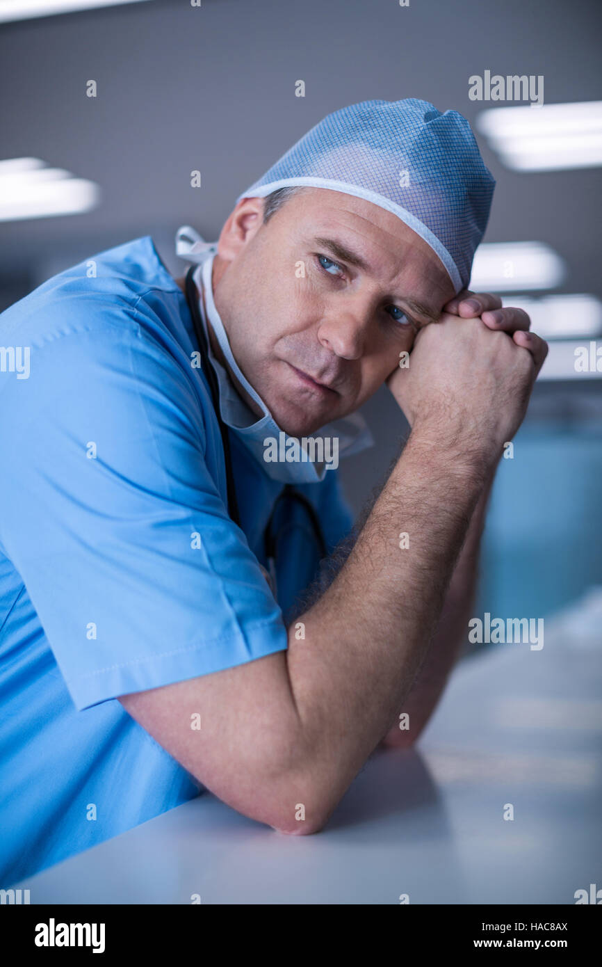 Unhappy surgeon leaning on desk Stock Photo - Alamy