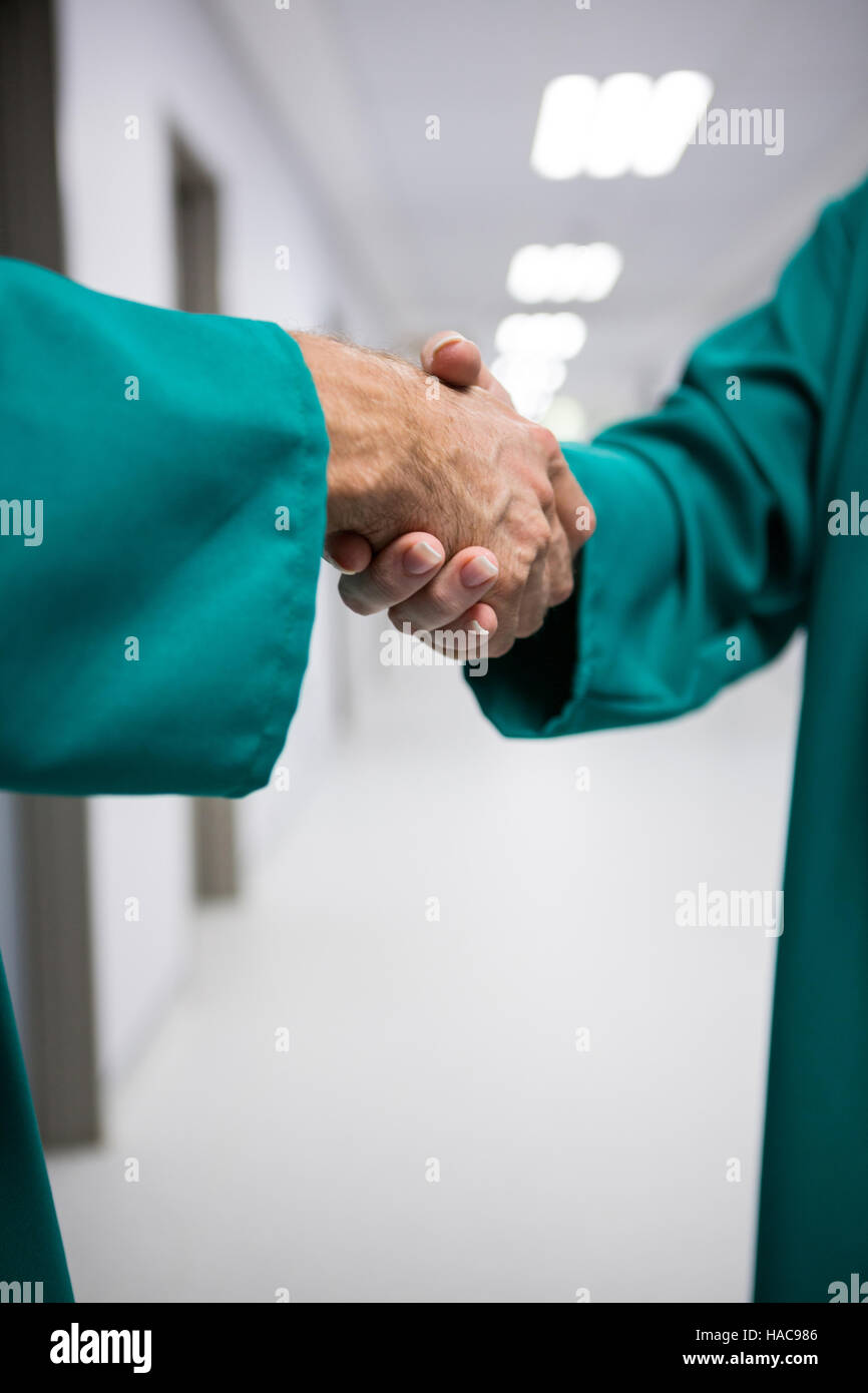 Mid section of surgeons shaking hands in corridor Stock Photo - Alamy