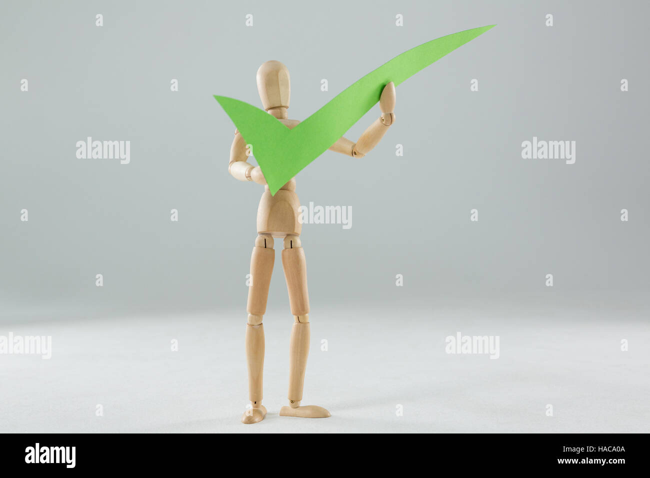 Wooden figurine holding a tick sign Stock Photo - Alamy