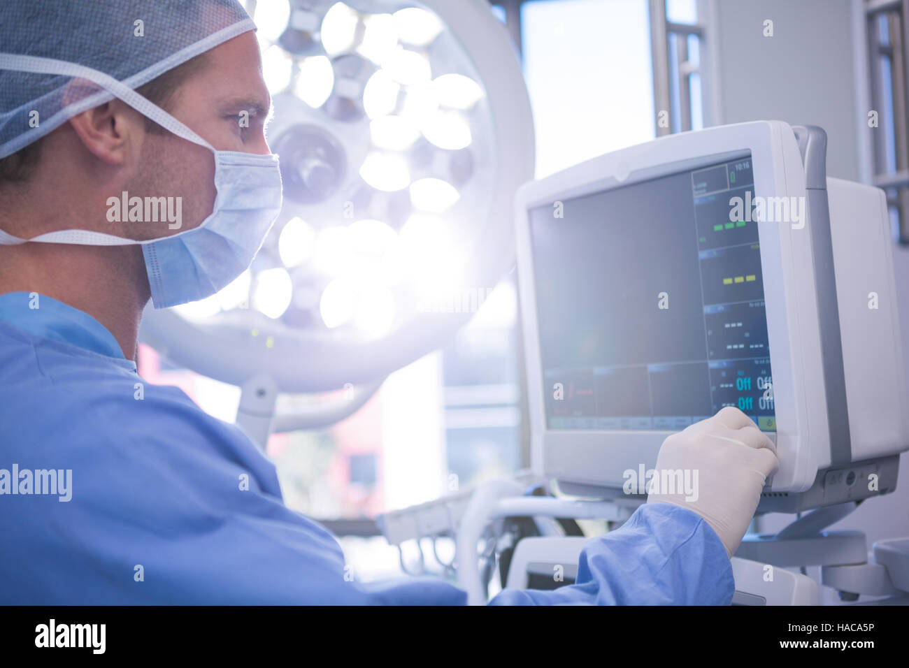 Male surgeon using patient monitoring machine in operation theater ...
