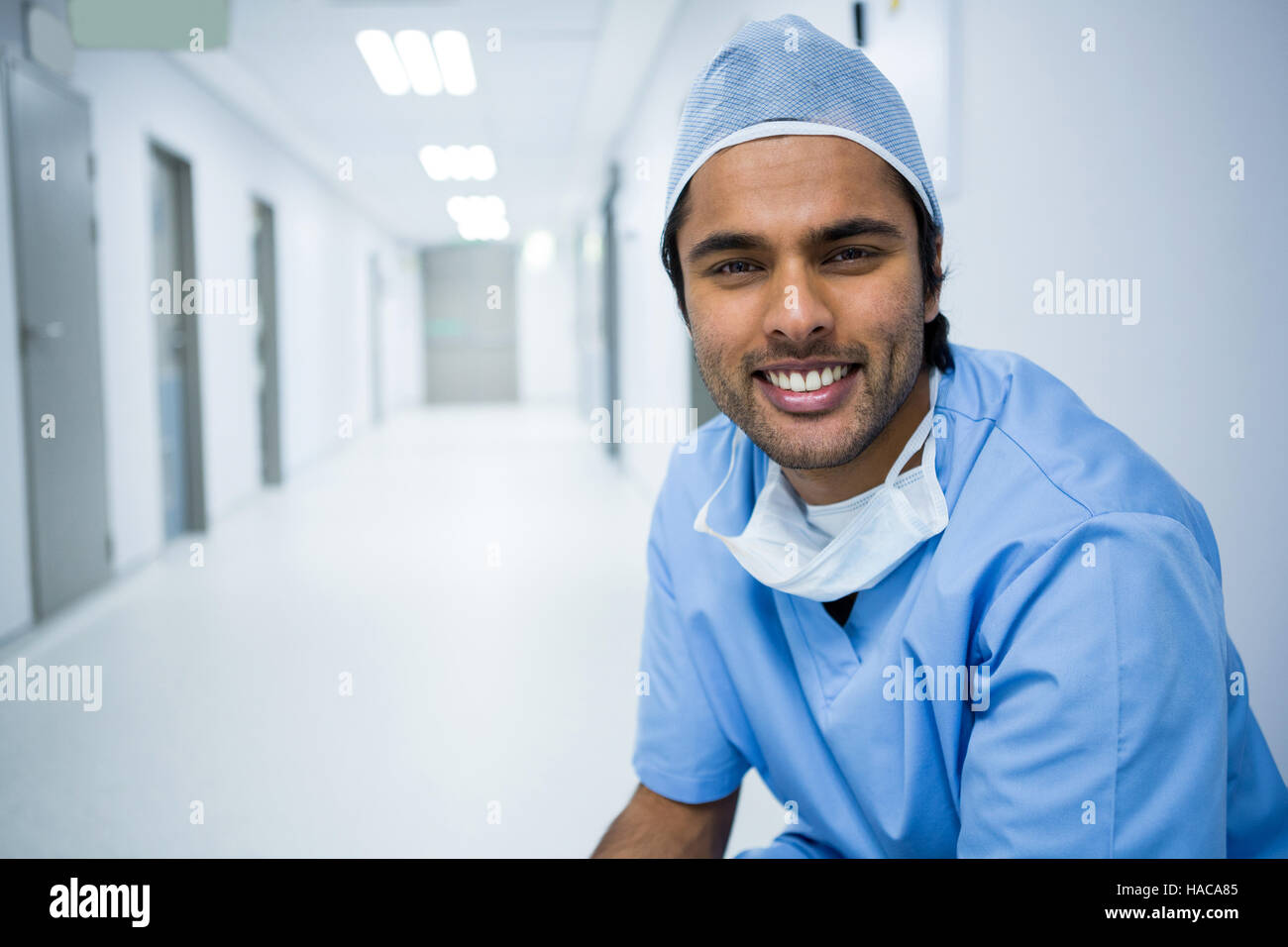 Portrait of smiling surgeon sitting in corridor Stock Photo - Alamy