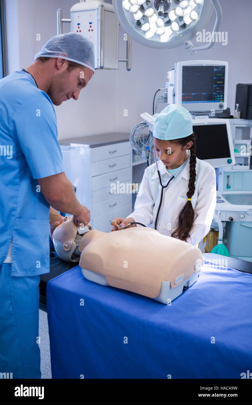 Doctor assisting girl in examining on dummy with stethoscope Stock ...