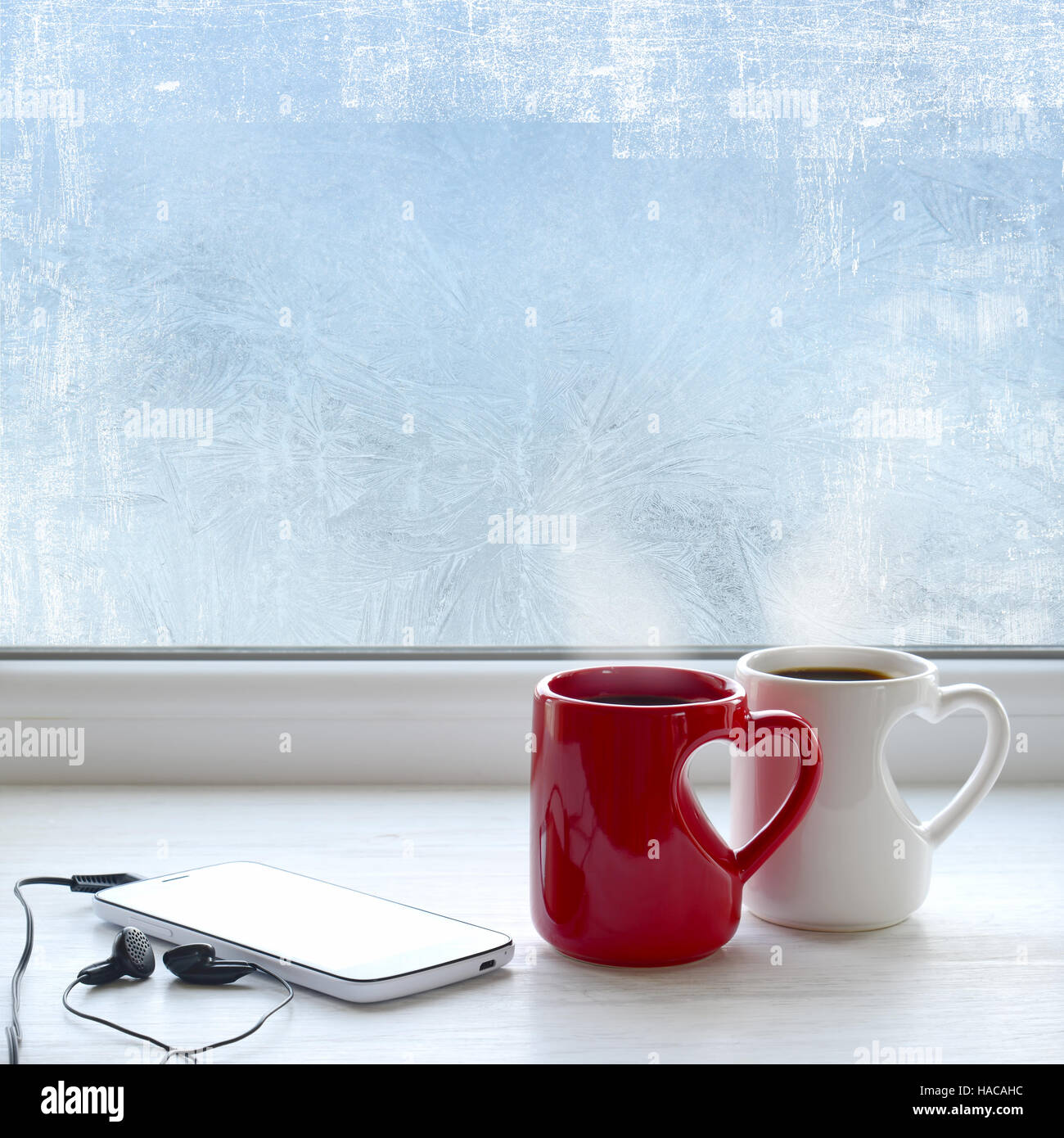 Cup of coffee on the window sill. In the background frosty pattern on ...