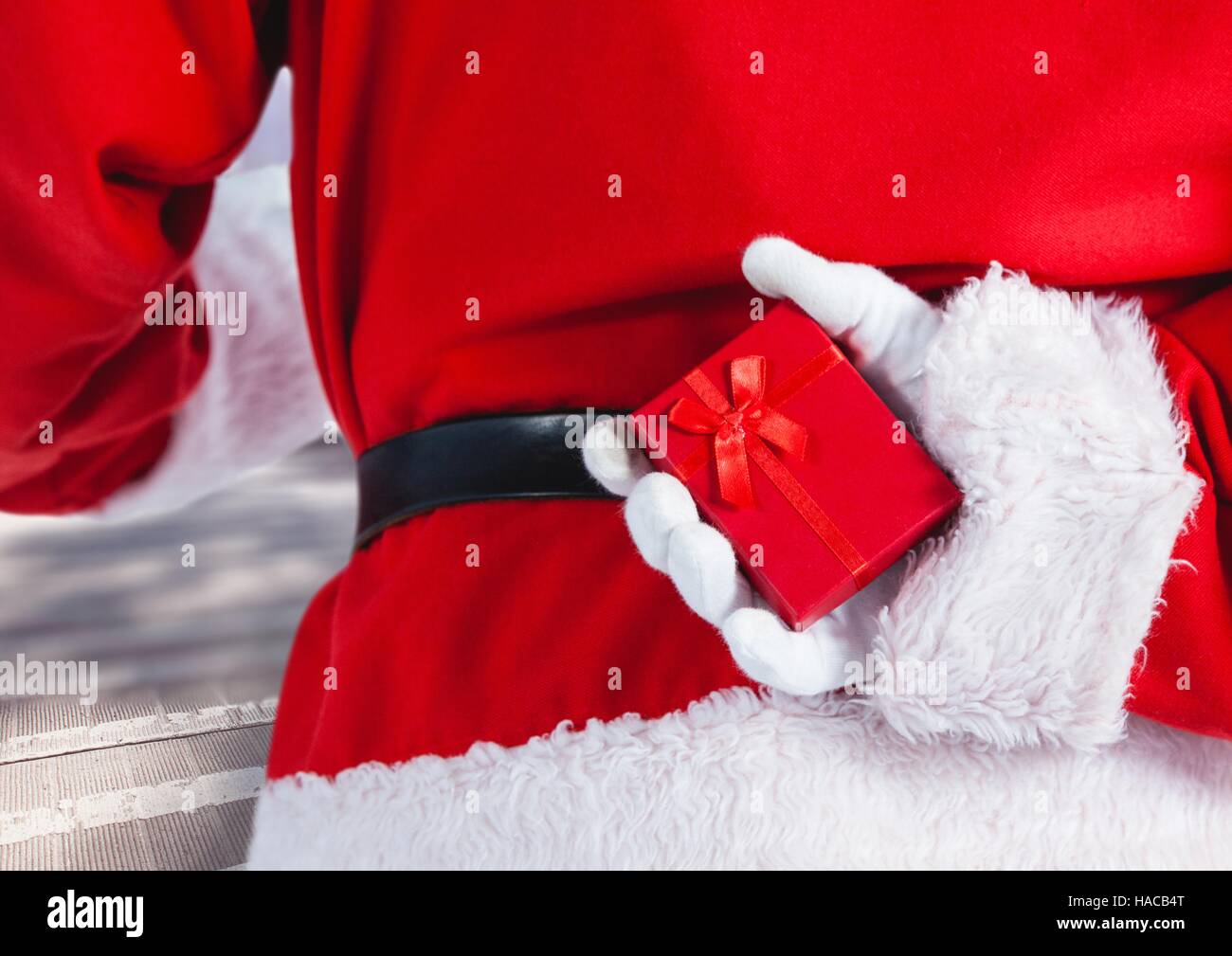 Santa claus hiding christmas gift behind his back Stock Photo - Alamy