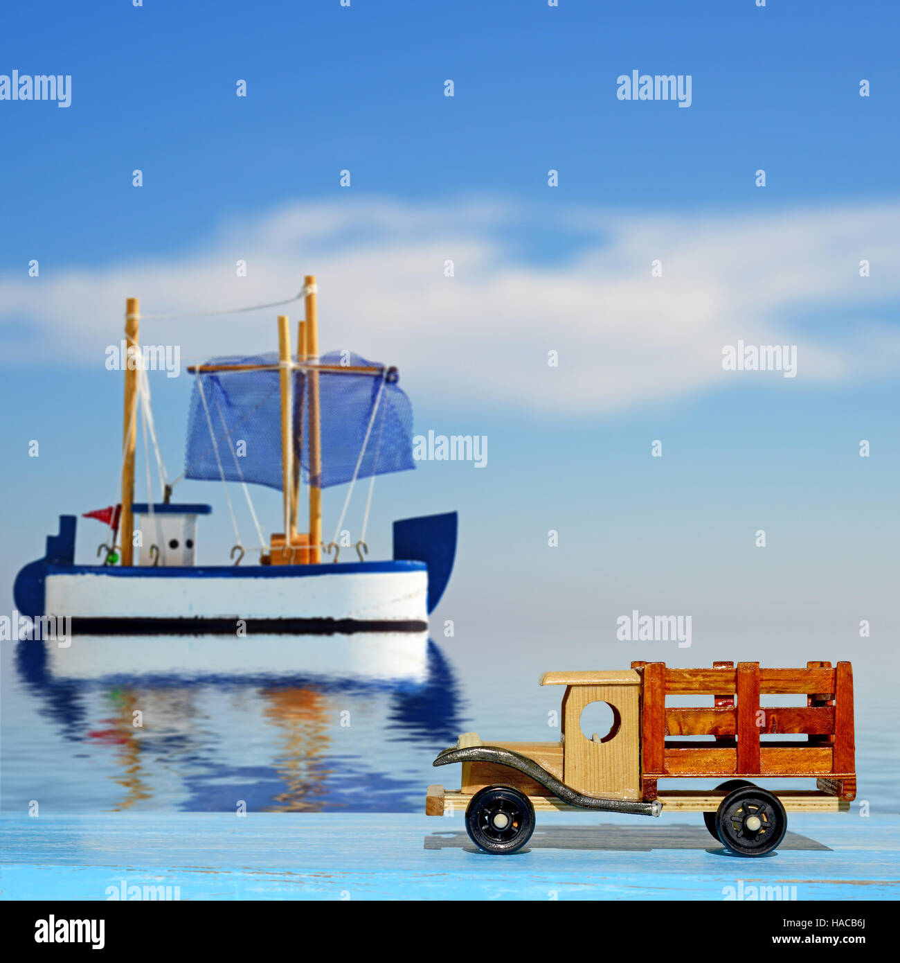 Toy car on a blue wooden surface and toy sailboat at sea Stock Photo ...