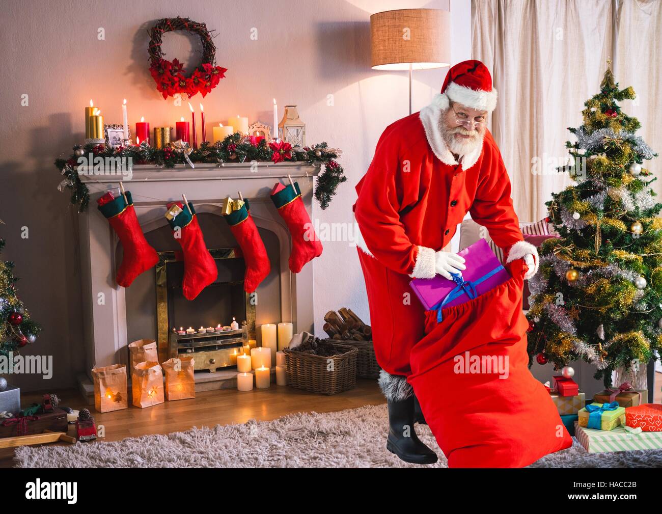 Santa putting christmas gifts in sack in living room Stock Photo - Alamy