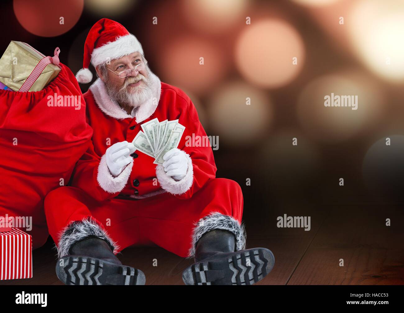 Santa claus with gift sack holding dollars while sitting on wooden ...