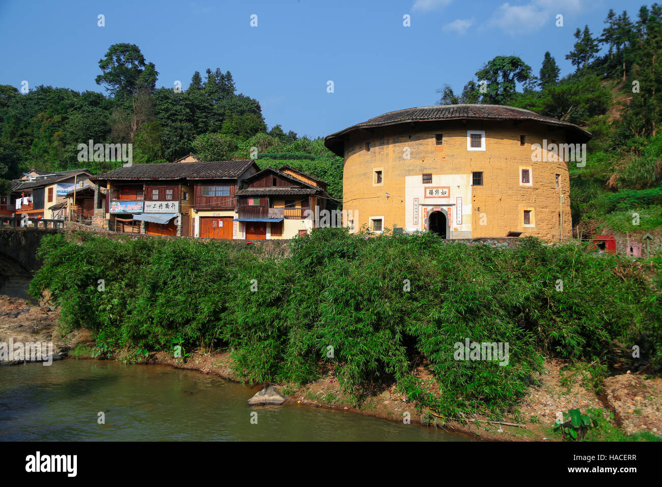 A small fujian earthen building (Tulou) beside other modern wood houses ...