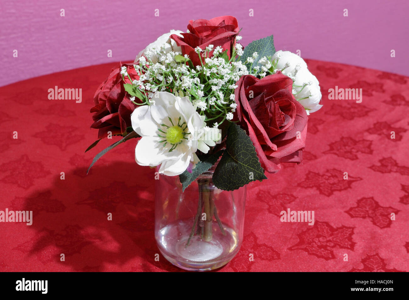Decorative plastic flowers in a glass jar with red table cloth Stock ...