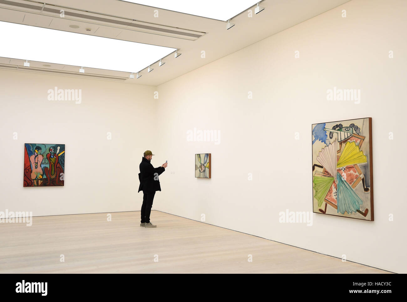 A man takes a photograph of work by Artist Ansel Krut displayed at a ...