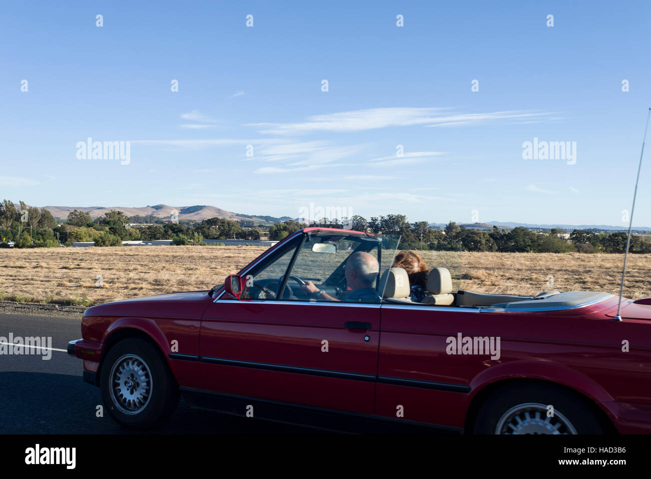 Couple driving on highway to Napa Valley, California in open roof ...