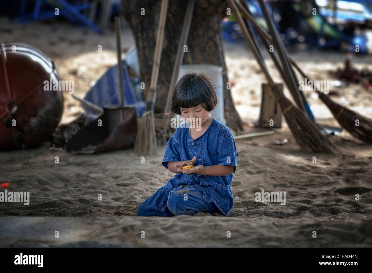 Child playing alone outside. Cute young Thai girl happy and content to ...