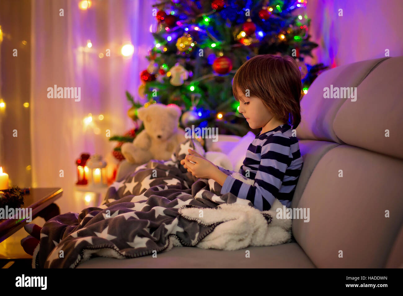 Cute sweet child, boy, playing on mobile phone under the blanket ...