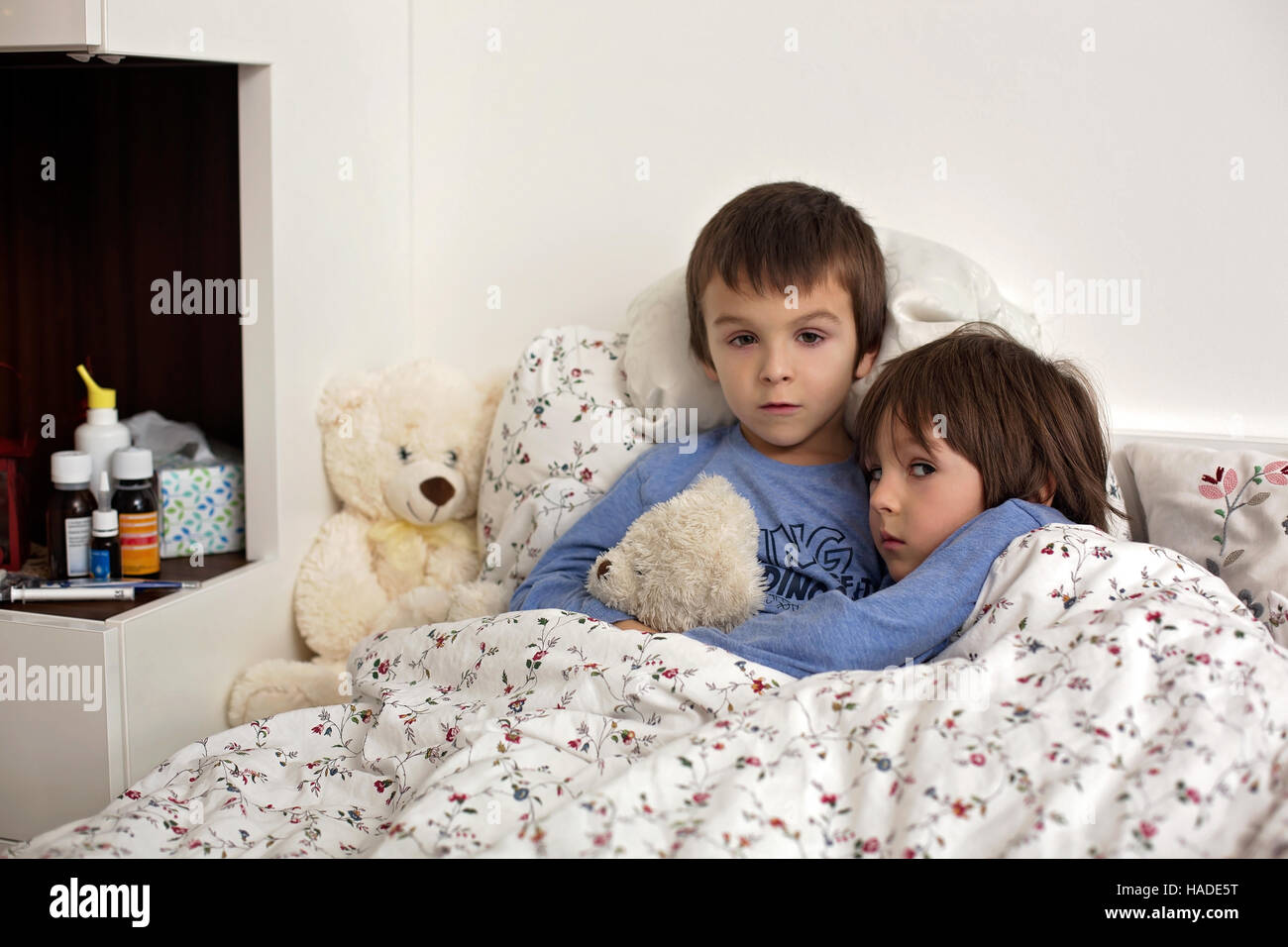 Two cute sick children, boys, staying in bed with fever, playing with ...