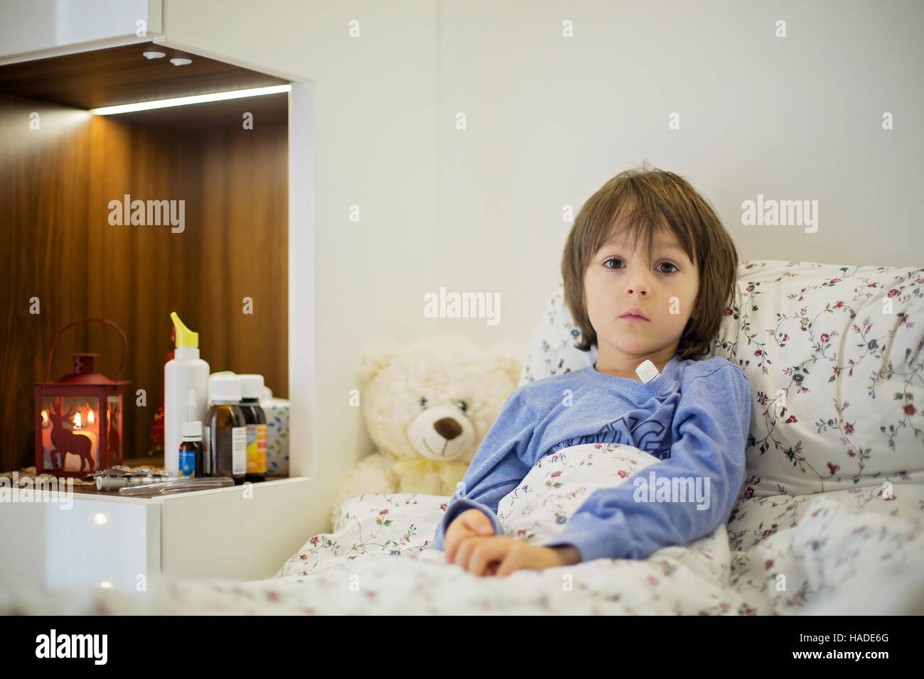 Cute sick child, boy, staying in bed, playing with teddy bear, giving ...