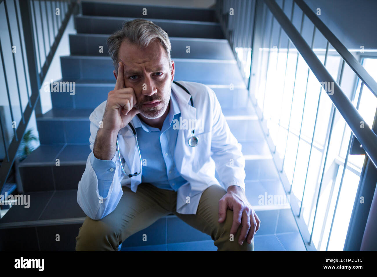 Portrait of sad doctor sitting on staircase Stock Photo - Alamy