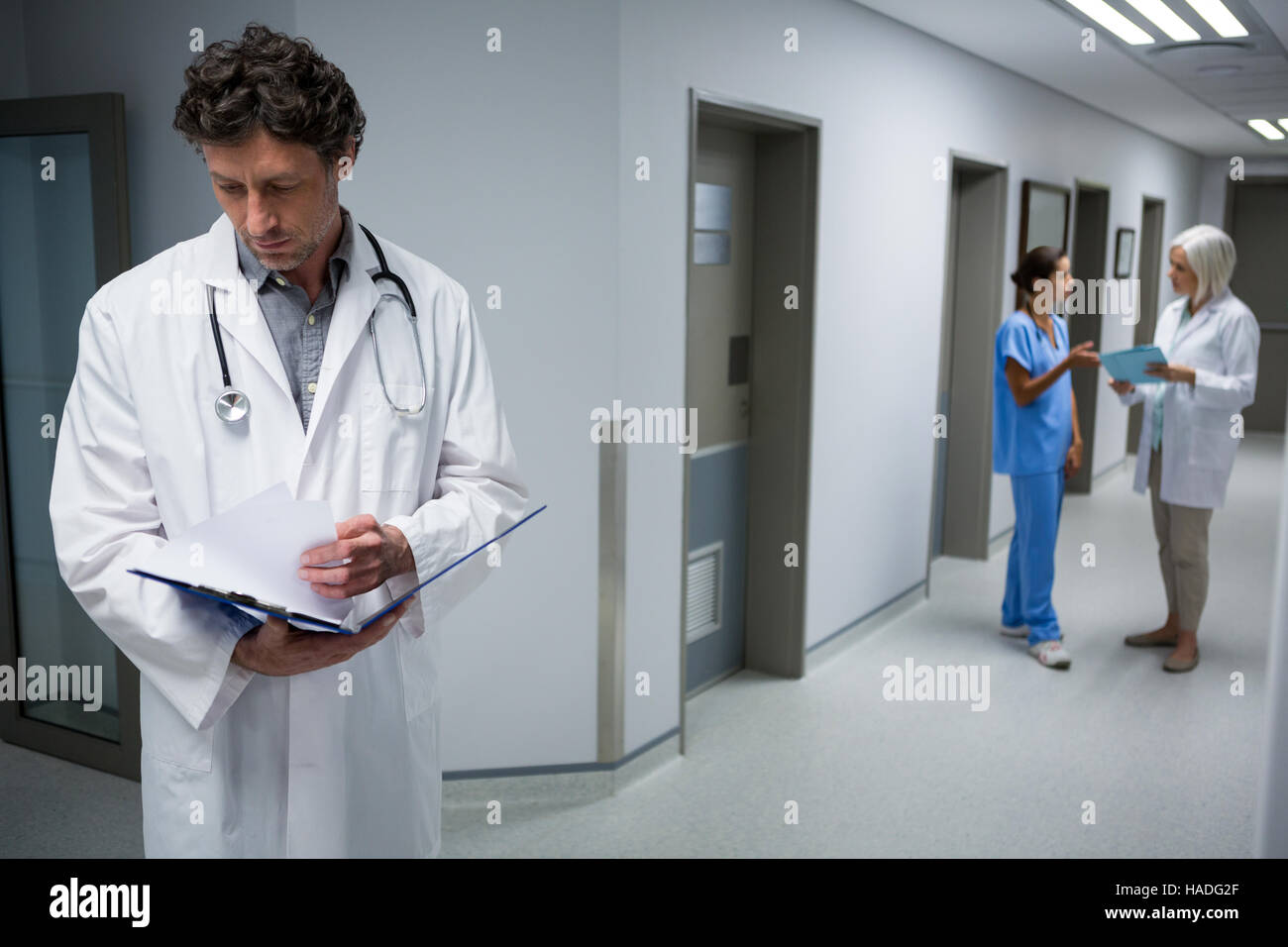 Doctor looking at medical report in corridor Stock Photo - Alamy