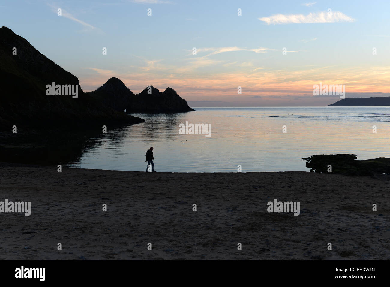 A lone figure walks the high tide line at Three cliffs bay, Gower ...