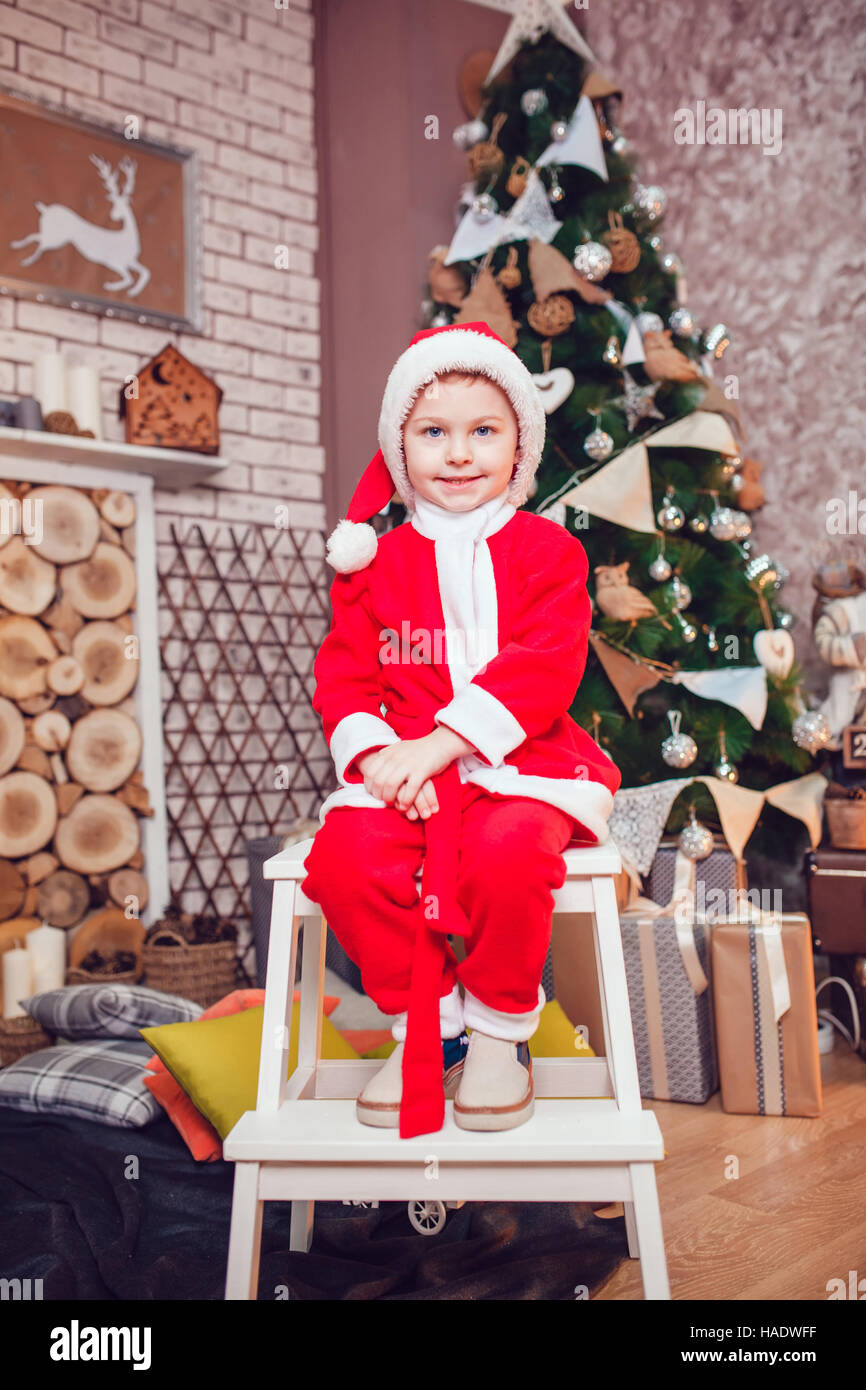 Little boy dressed as Santa Claus sitting in Christmas decoration. New ...