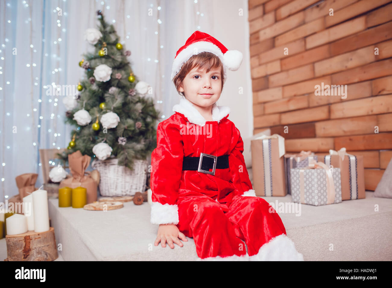 Little boy dressed as Santa Claus sitting in Christmas decoration. New ...