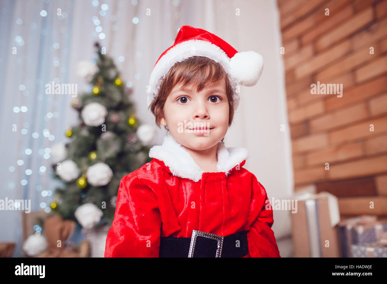 Little boy dressed as Santa Claus sitting in Christmas decoration. New ...