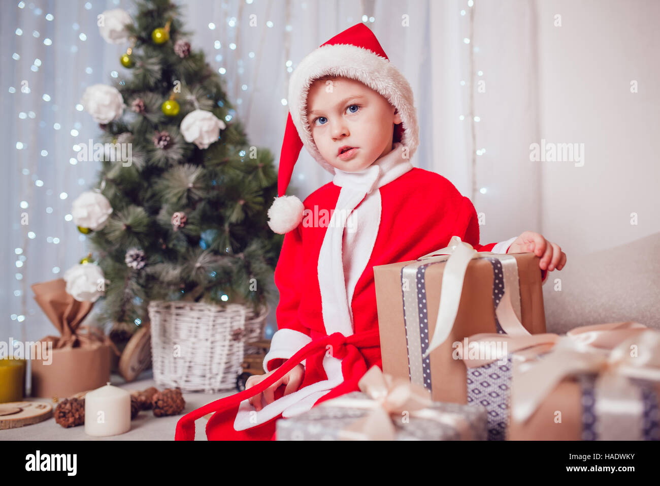 Little boy dressed as Santa Claus sitting with gifts in Christmas ...