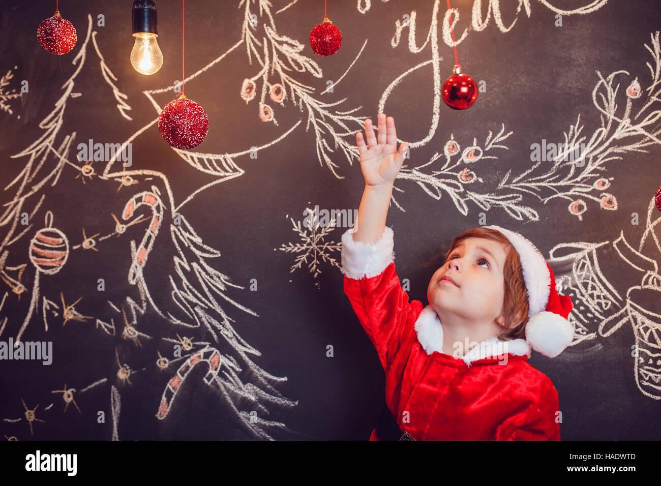Little boy dressed as Santa Claus standing on dark background with ...