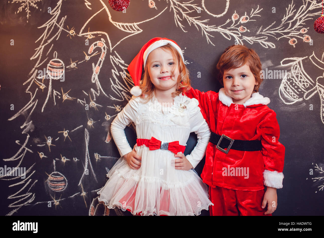 Children dressed as Santa Claus standing on dark background with ...