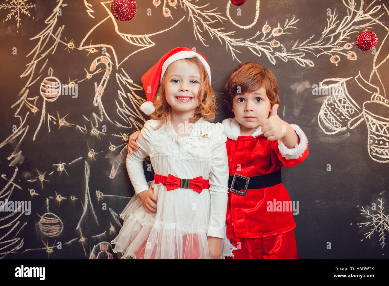 Children dressed as Santa Claus standing on dark background with ...