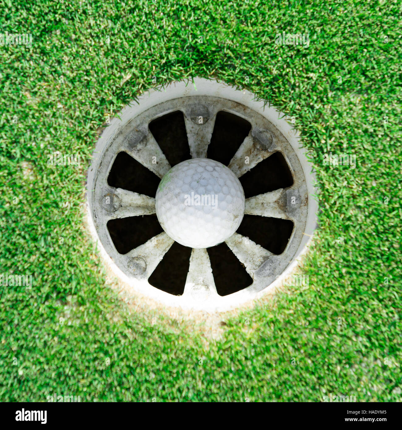 golf ball into the hole square composition Stock Photo - Alamy