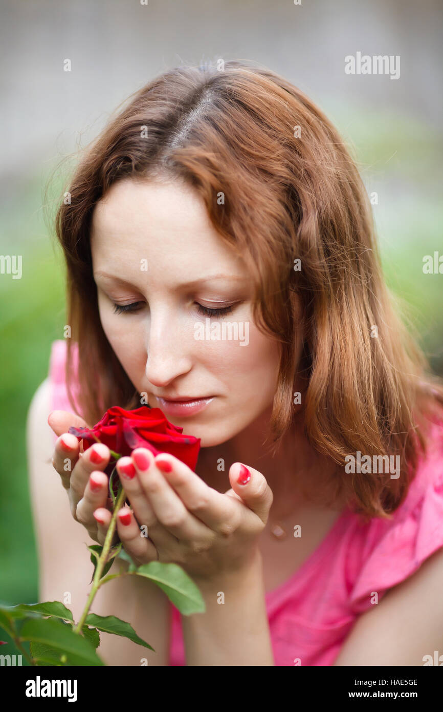 Portrait of young woman smelling rose in garden Stock Photo - Alamy